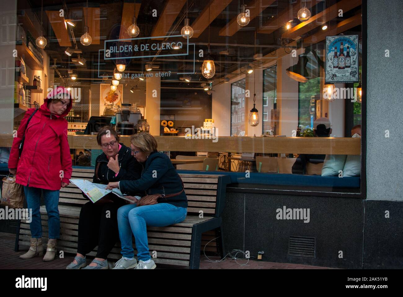 Three women seated on the bench in front of a restaurant looking for ...