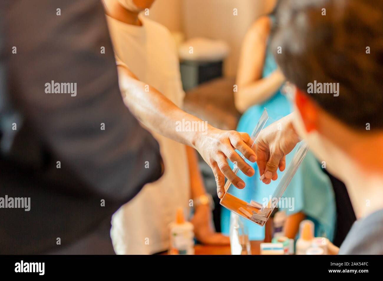 Man taking paper piece from plastic box with friends in background ...