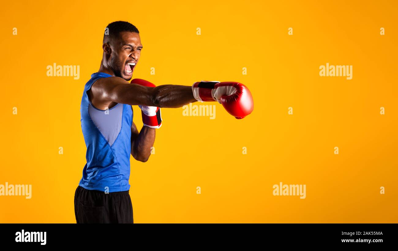 Ready For Fight. Aggressive black man practicing boxing punches in ...
