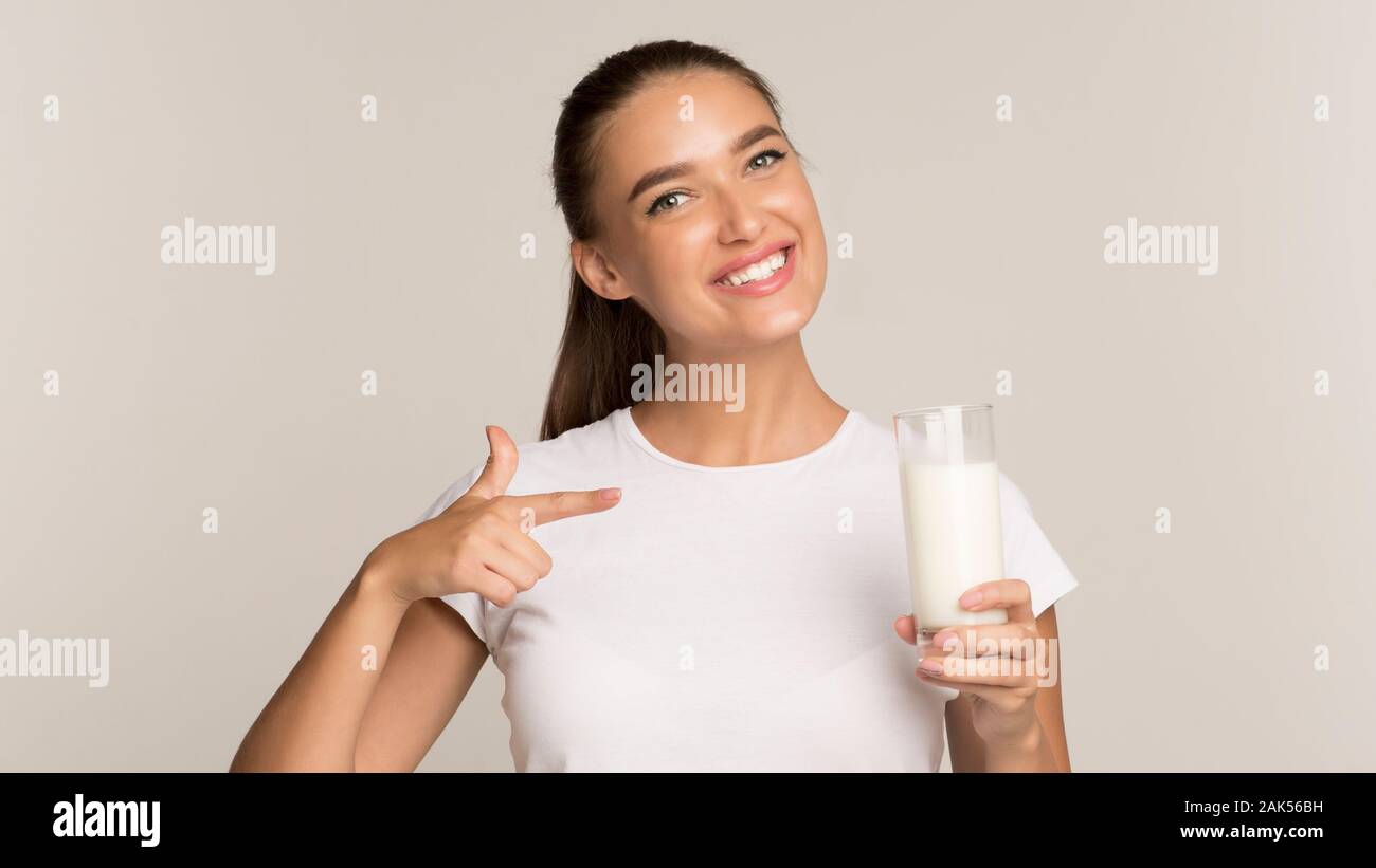 Cheerful Young Lady Holding Milk Pointing Finger At Glass Recommending ...