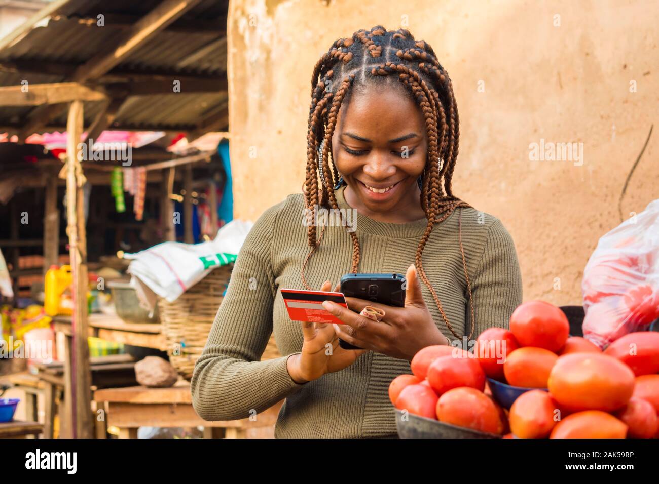 young african woman selling in a local african market using her mobile ...