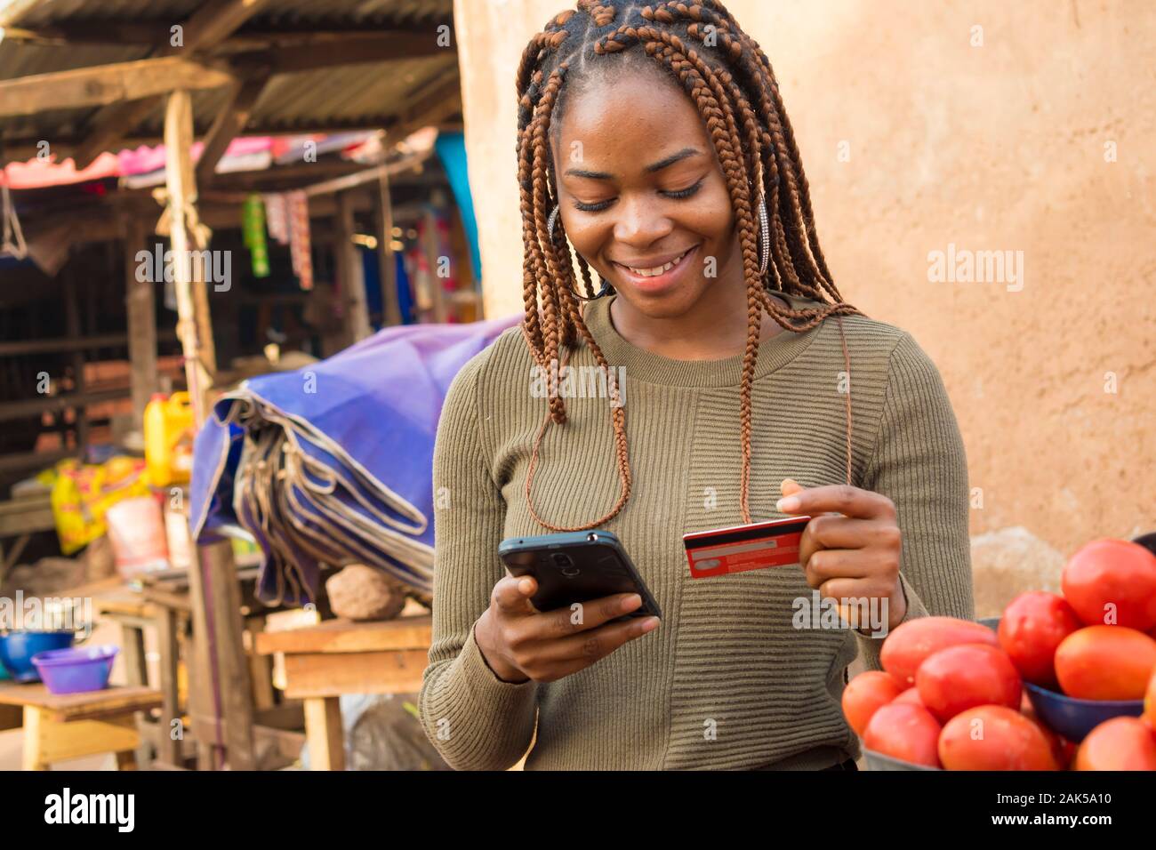 young nigerian woman selling in a local nigerian market using her ...