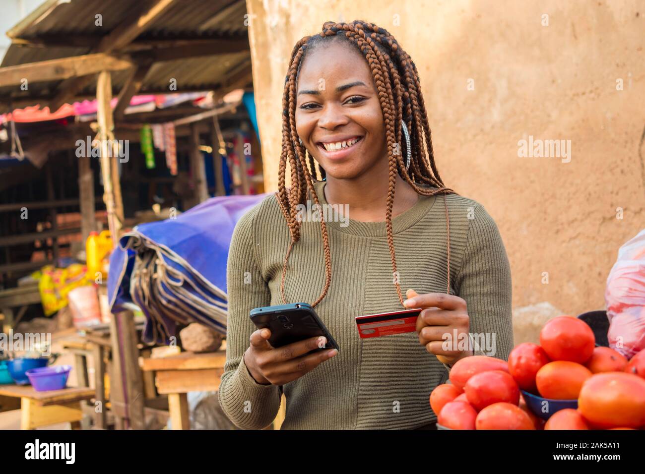 nigerian woman selling in a local nigerian market using her mobile ...