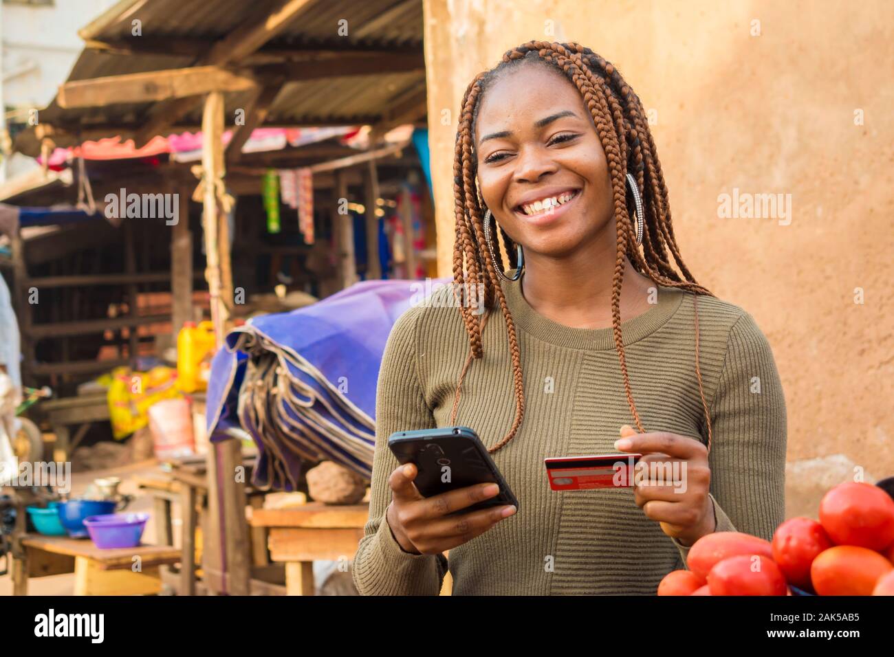 nigerian lady selling in a local nigerian market using her phone and ...