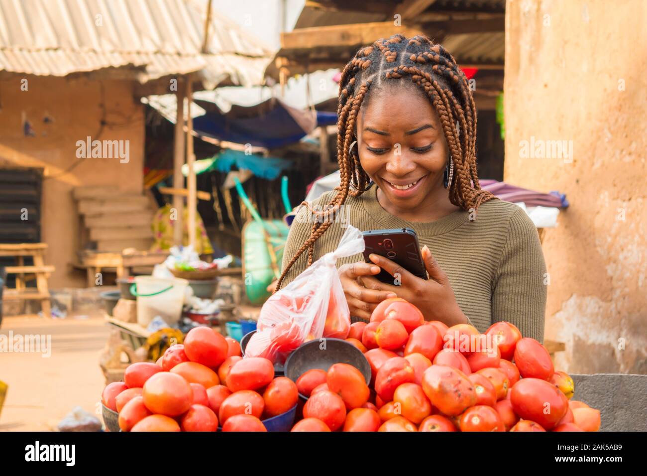 young african woman in a local african market viewing content on her ...