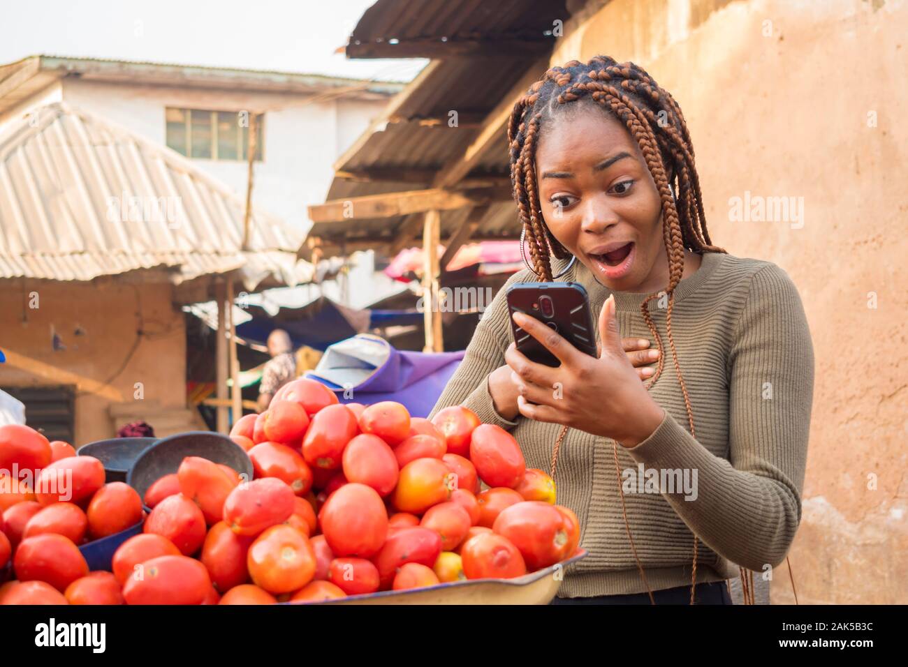 excited young african woman in a local african market viewing content ...