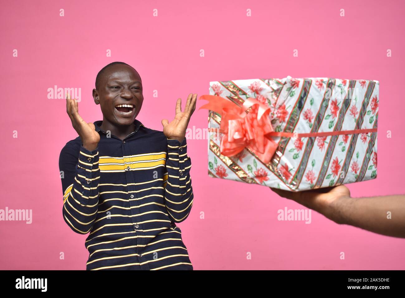 young black man feeling excited as as someone stretches a gift to him ...