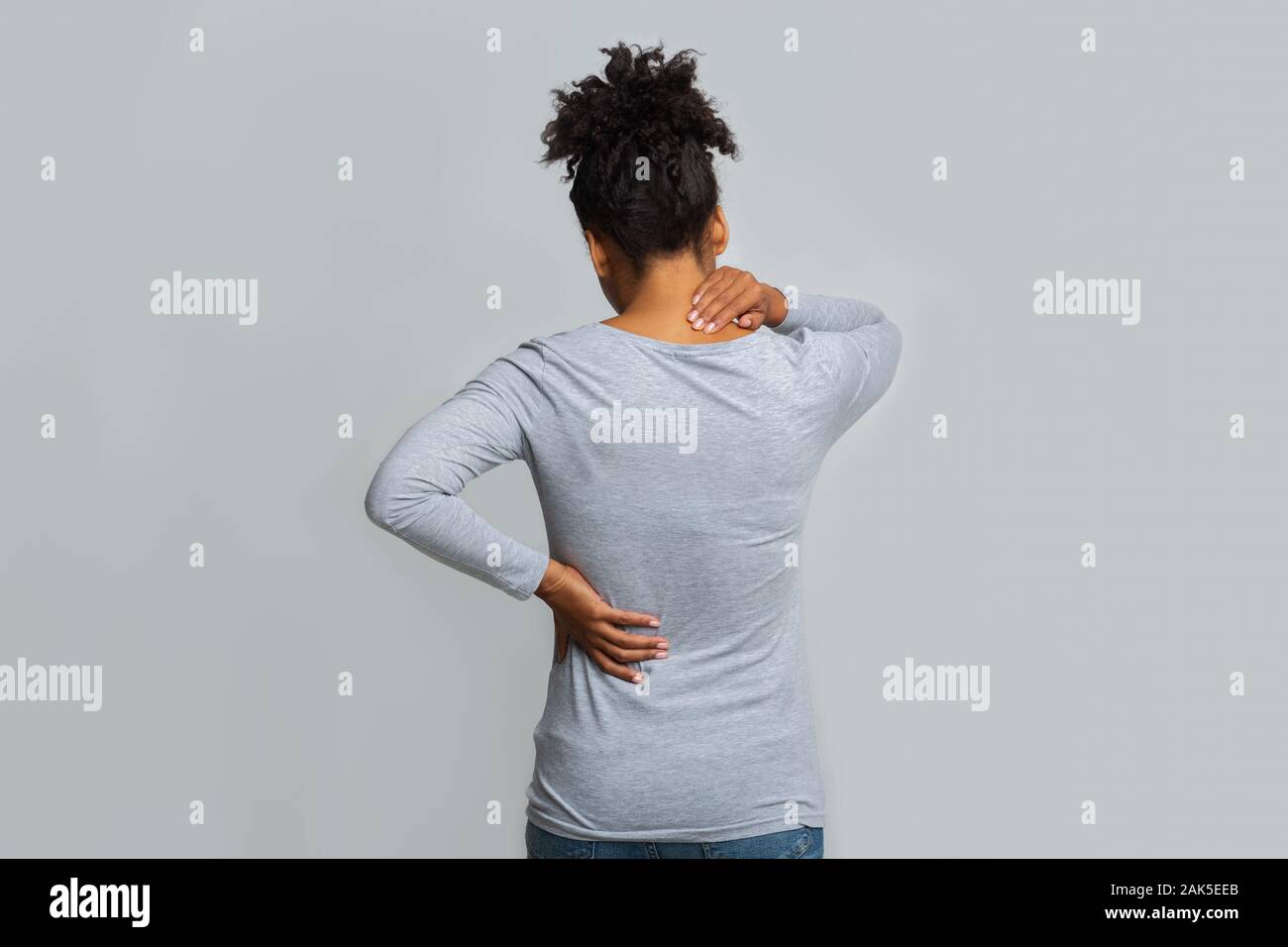 African woman with neck and back pain, rubbing her painful body over ...