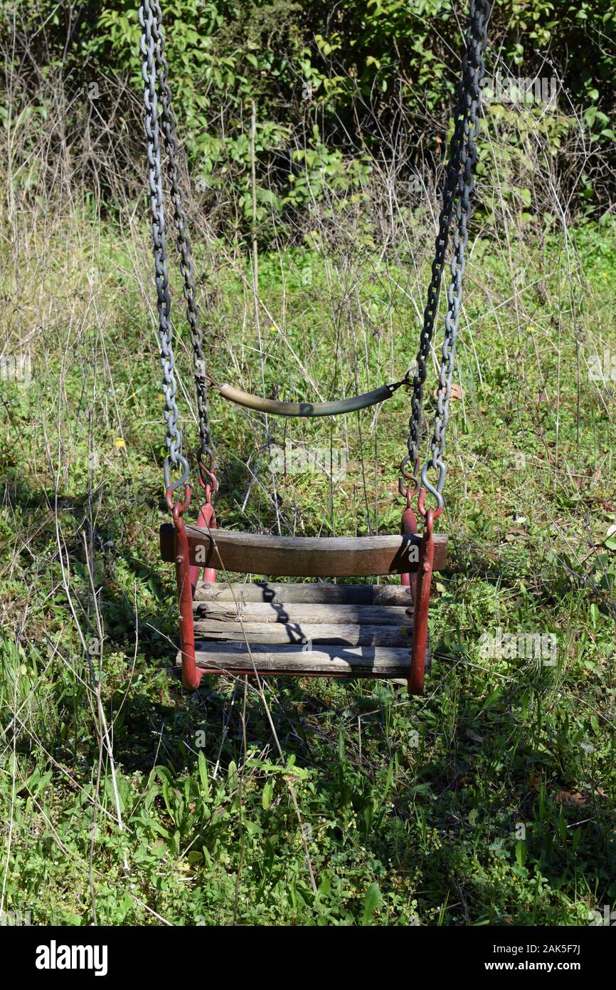 Old swing in overgrown garden of abandoned playground Stock Photo - Alamy