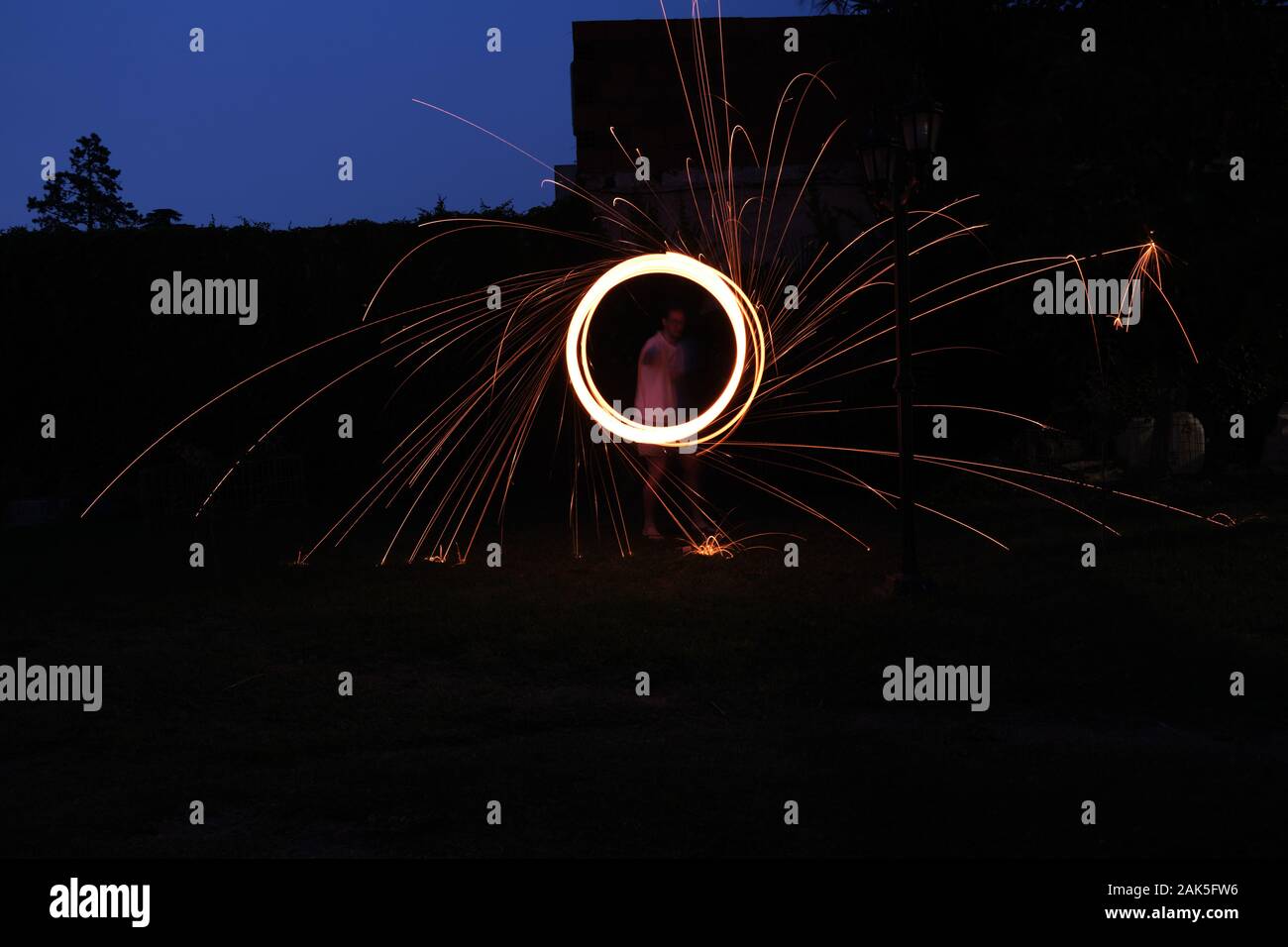 a long exposure photography of an steel wool on fire going in circles ...