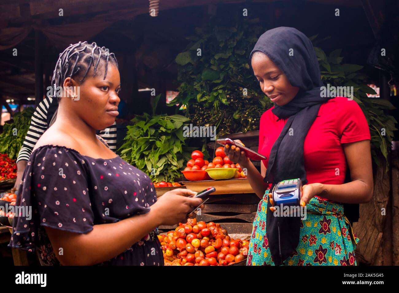 African woman shopping food stuff in a local market paying by doing ...