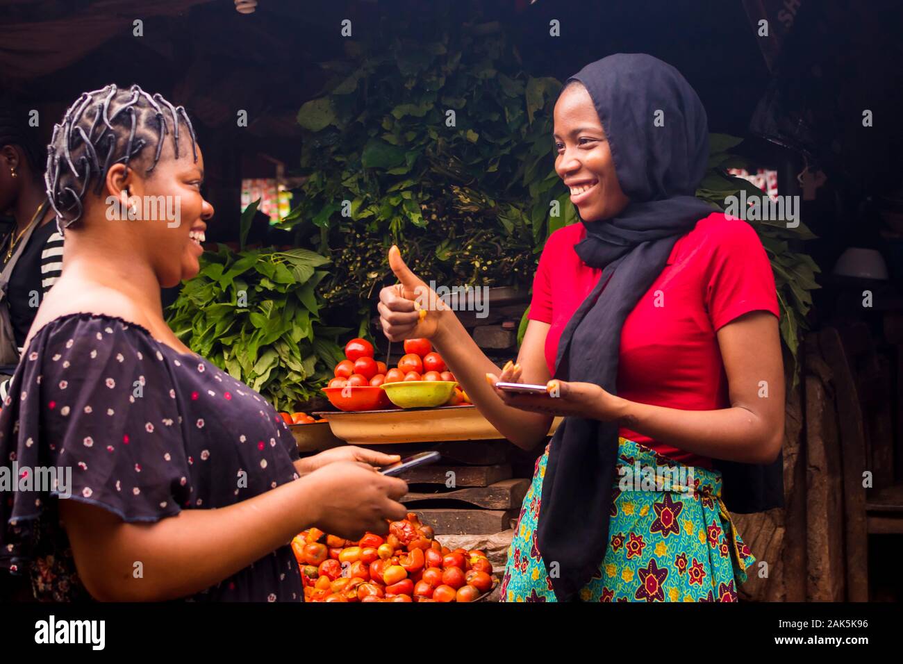 african woman selling in a local food market gives a thumbs up to a ...