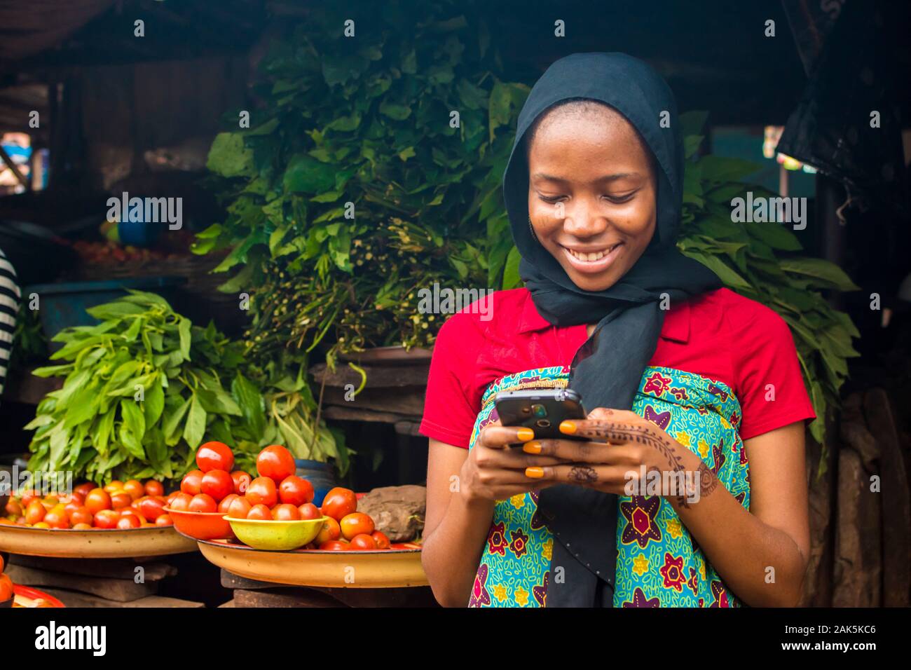 young african woman selling in a local market smiling while using her ...