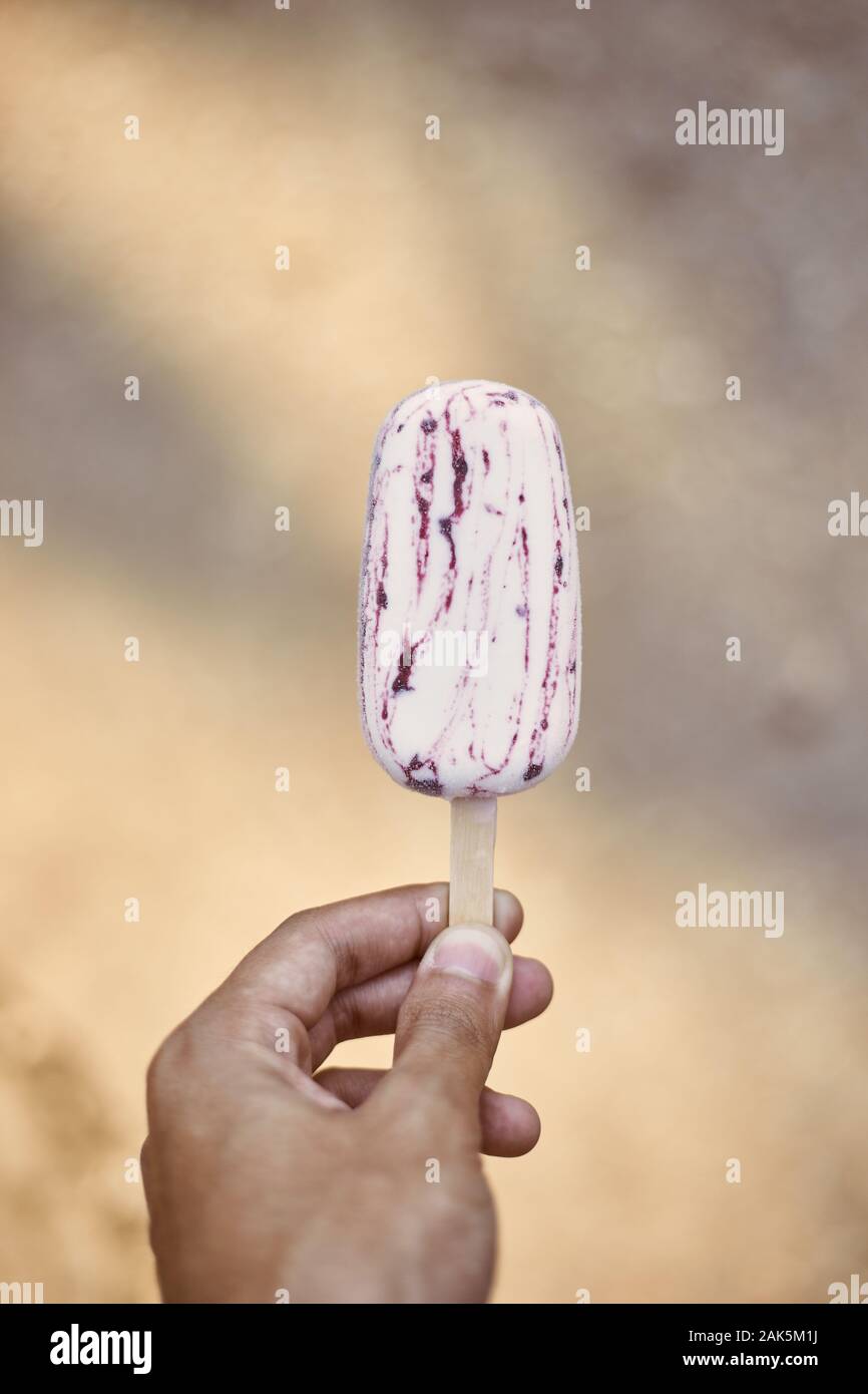 Hand holding popsicle on background Stock Photo - Alamy