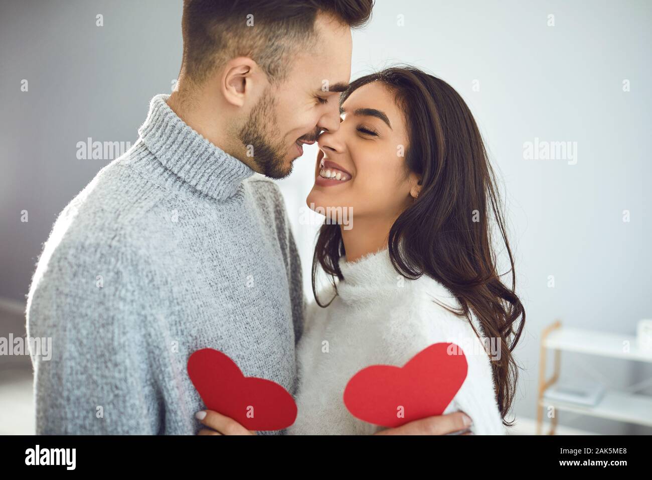 Valentine's day. Loving couple with hearts in hand cuddle in the room ...