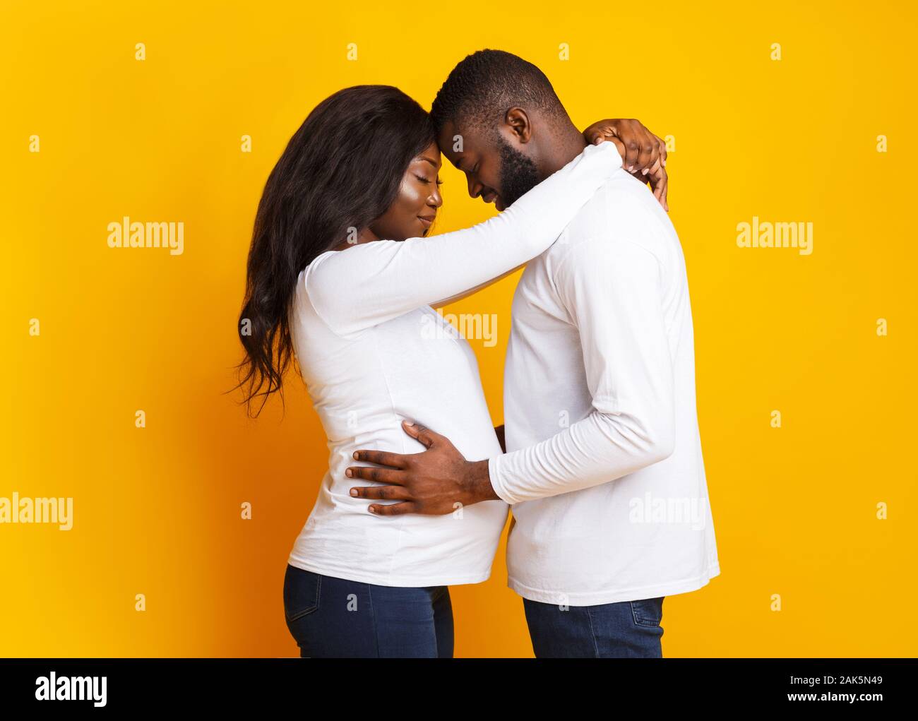 Young married african couple cuddling over yellow background, touching ...