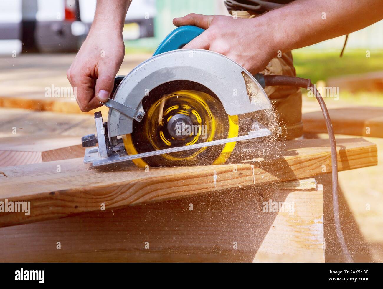 Builder saws a board with a circular saw in the cutting a wooden plank ...