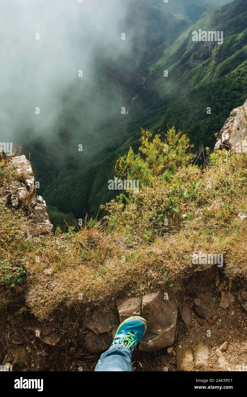 Foot over rock on the edge of deep rocky cliffs at the Fortaleza Canyon ...