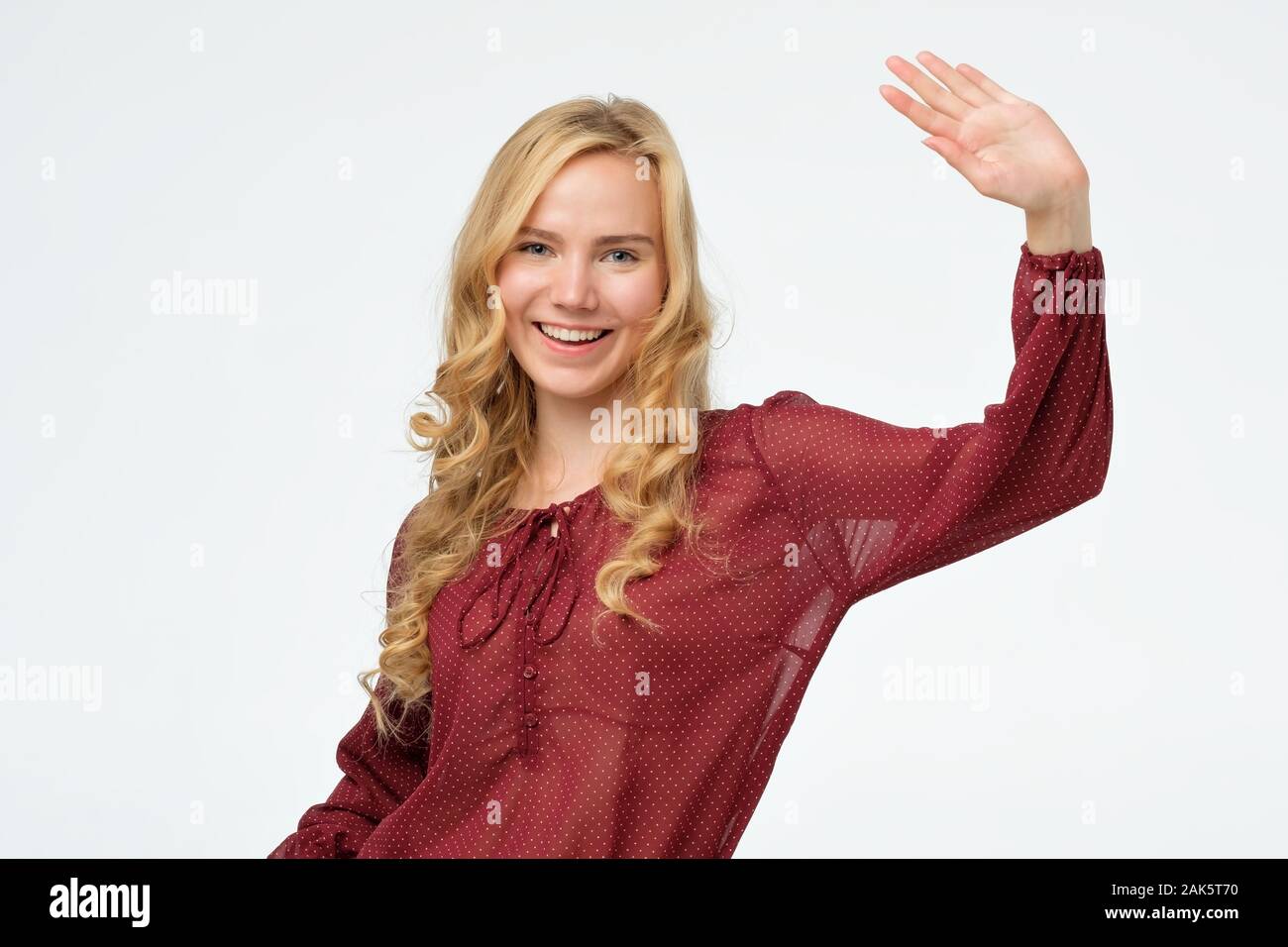 Attractive friendly looking young blonde female smiling happily, saying ...