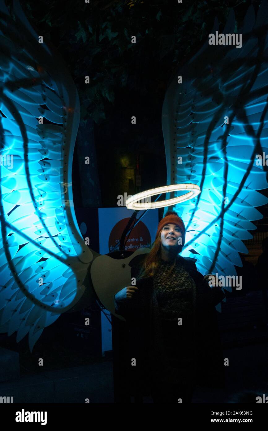 A young woman poses under a glowing halo in a night-lit art ...