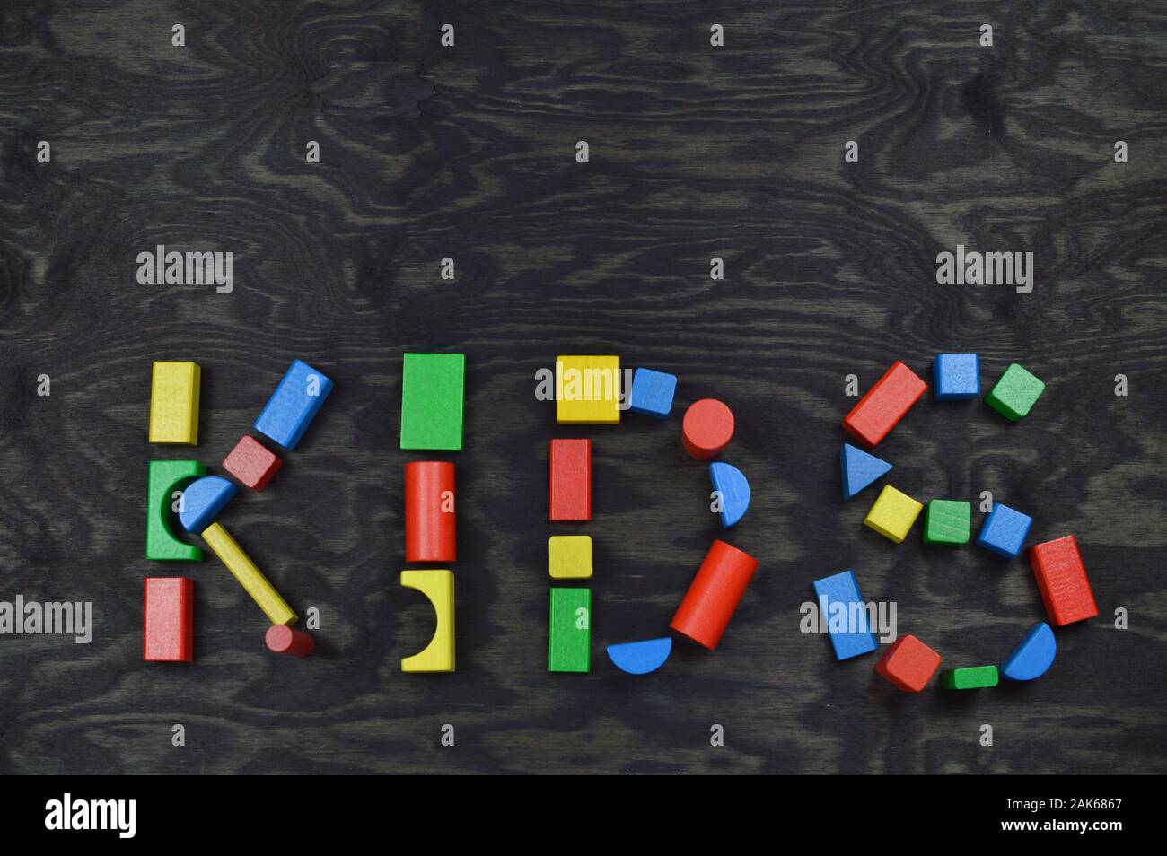 the word KIDS out of colorful wooden toy blocks on black wooden ...