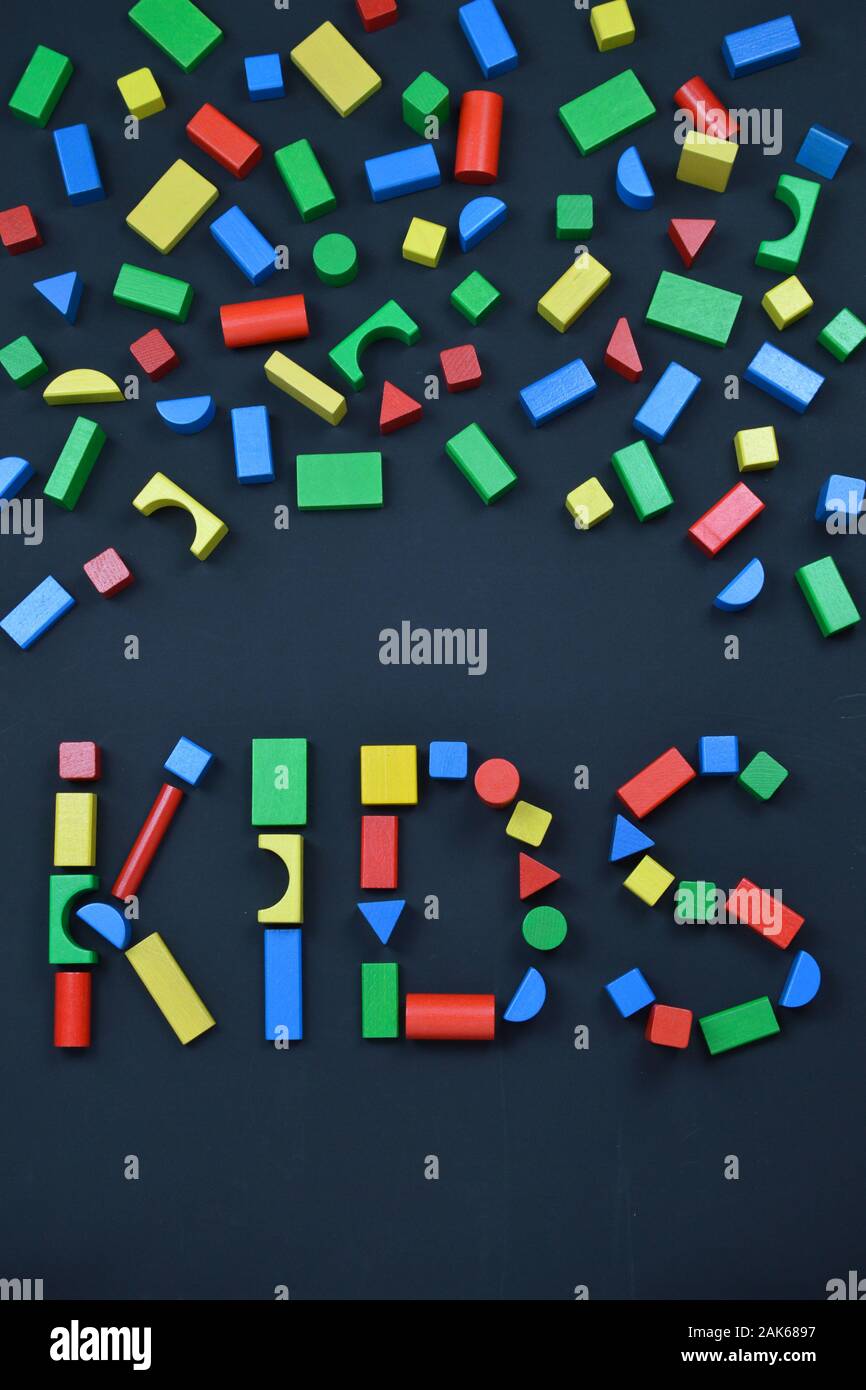 the word KIDS out of colorful wooden toy blocks on black background ...