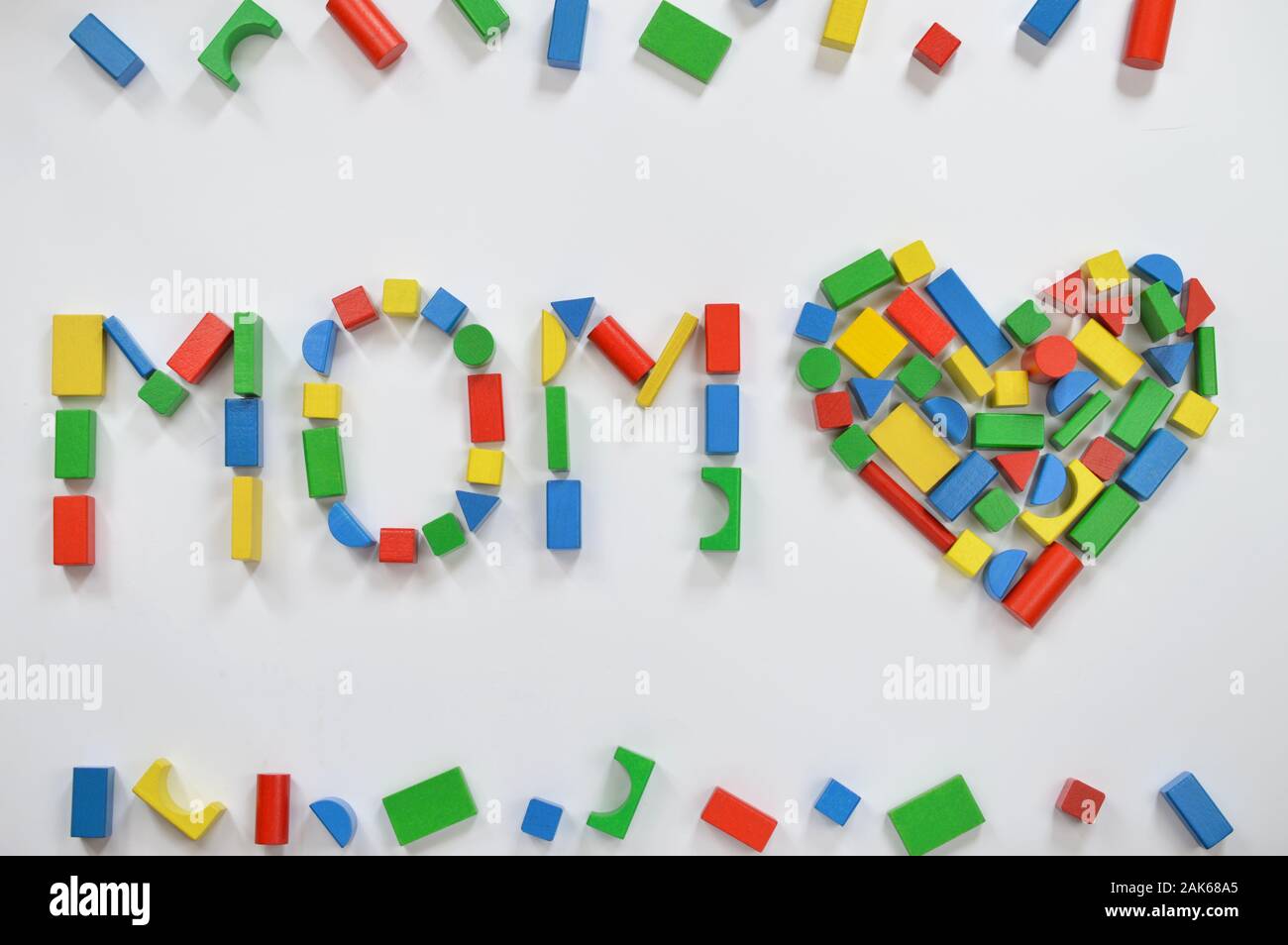 colorful wooden toy blocks lettering the word MOM and a heart on white ...