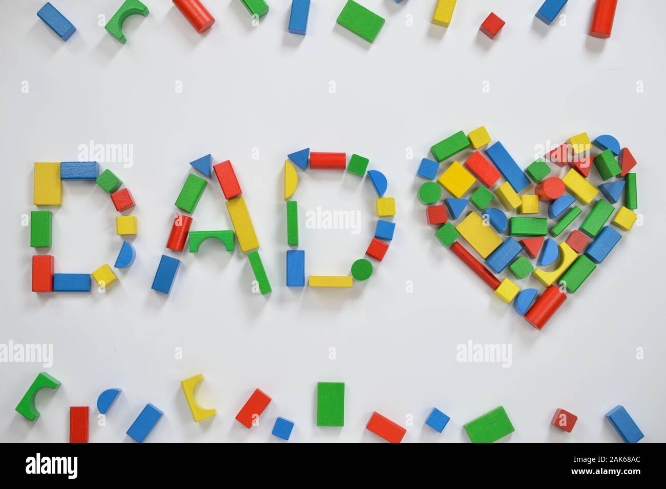 colorful wooden toy blocks lettering the word DAD and a heart on white ...