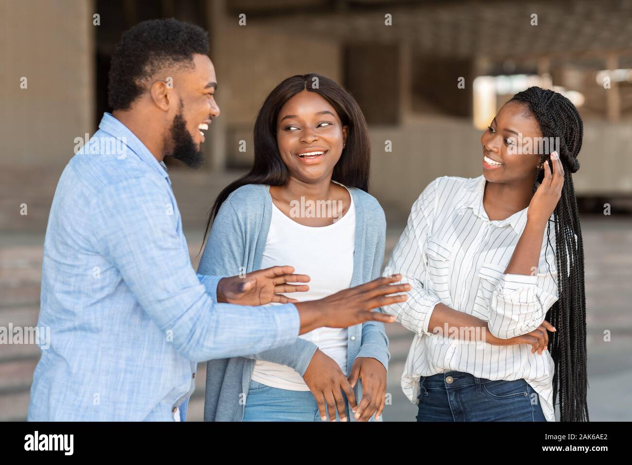 Three happy afro friends chatting and laughing outdoors in the street ...