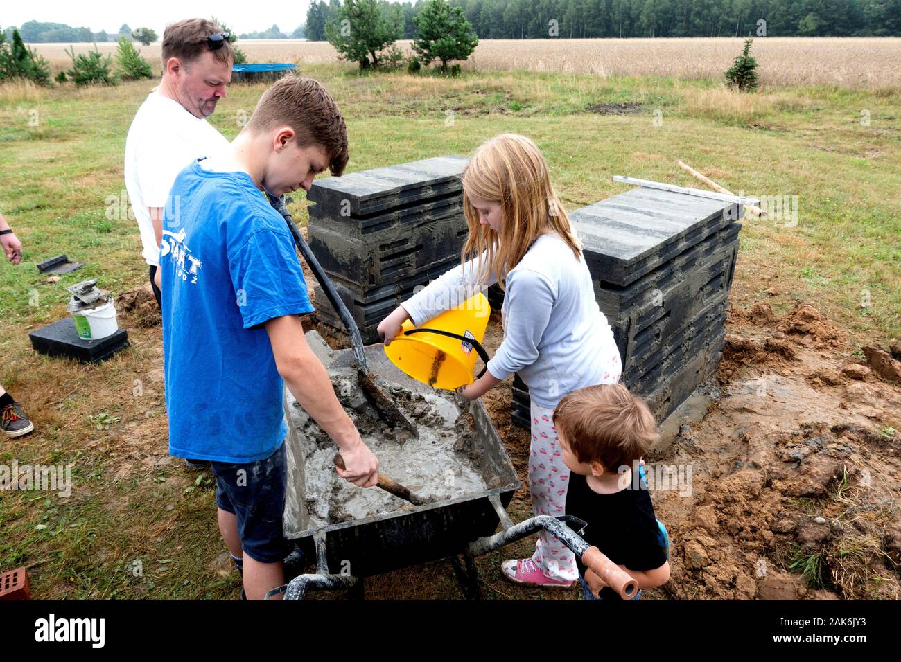 Uncle, nephews, niece mixing cement for building an outdoor family ...