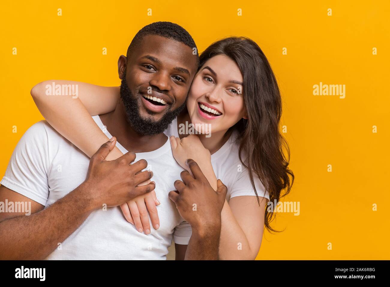 Portrait Of Romantic Interracial Couple Hugging And Looking At Camera