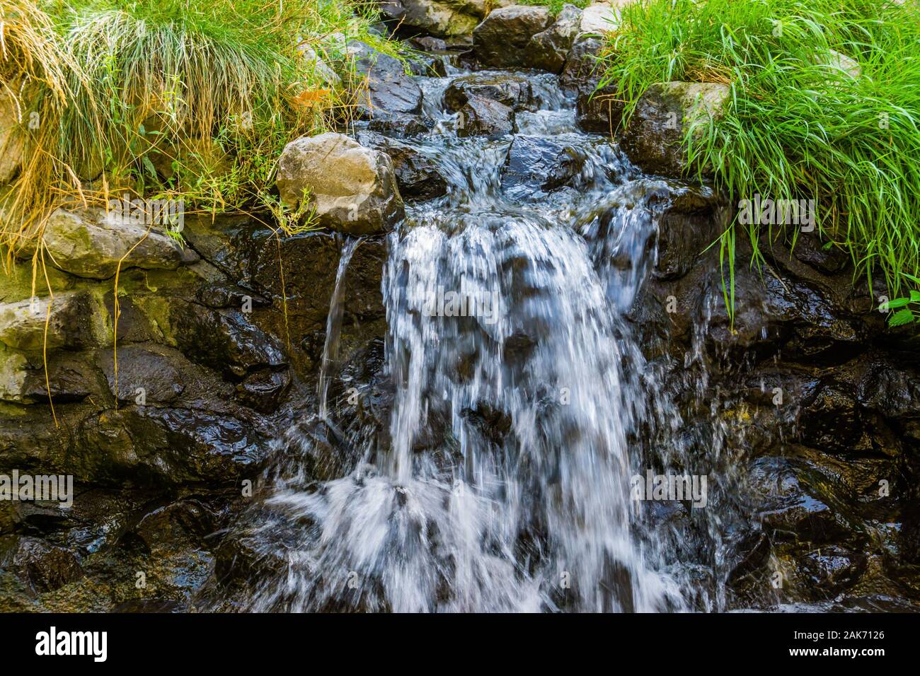 small streaming waterfall, water flowing over rocks, beautiful nature ...