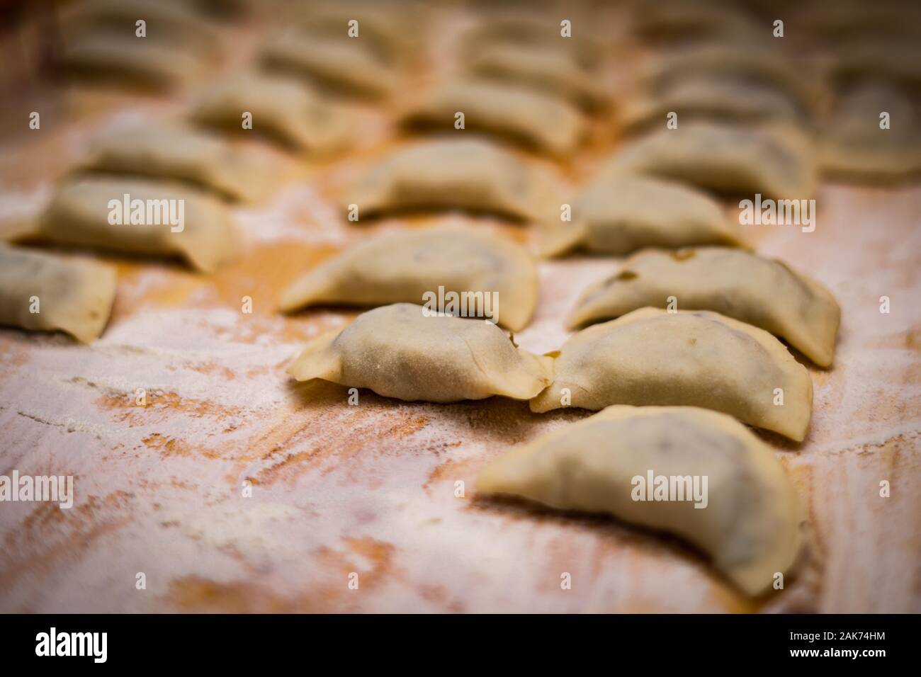 Pierogi. Dumplings stacked side by side on a wooden board moments ...