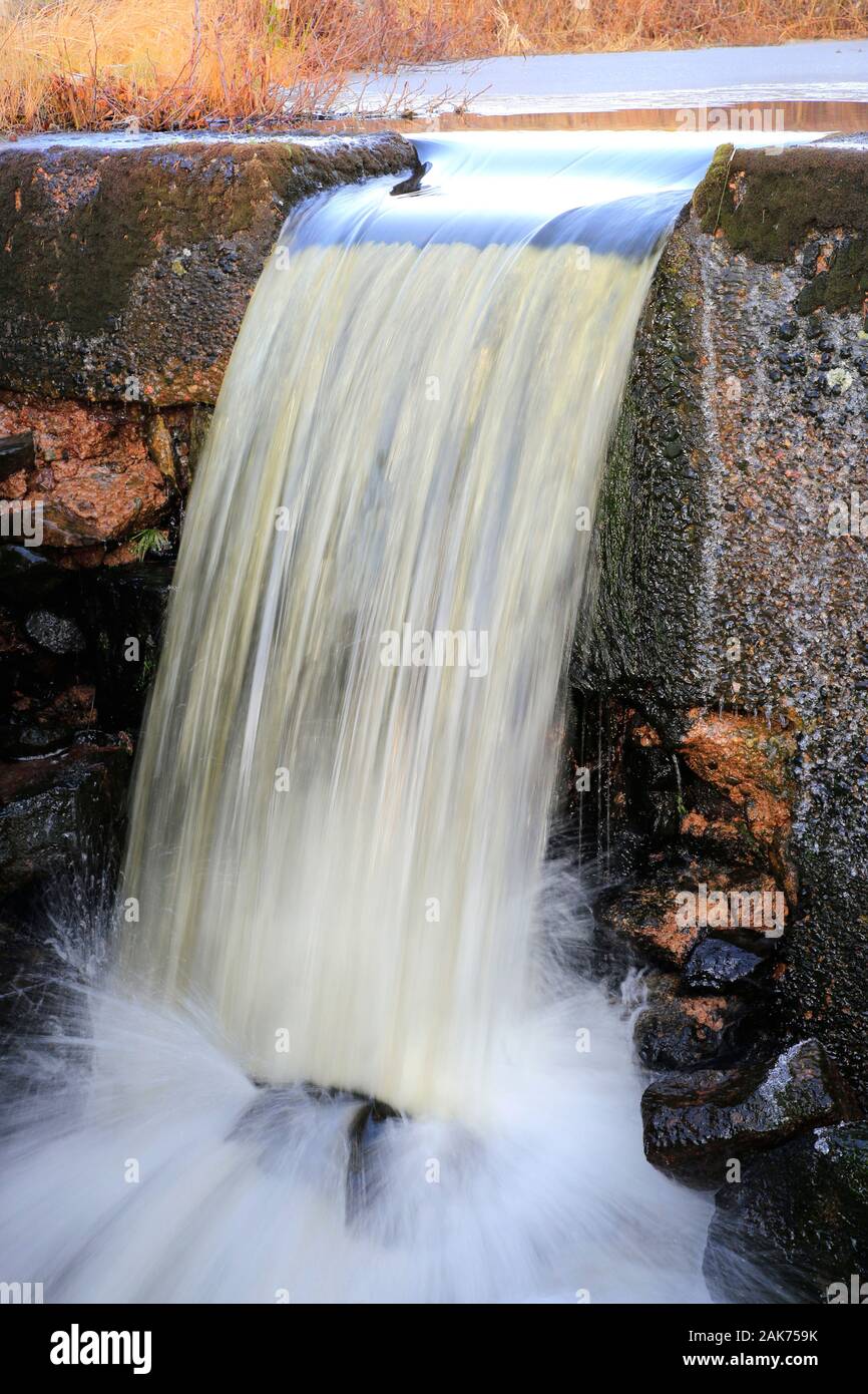 Small brook falling from a rural pond in winter, long exposure. Salo ...