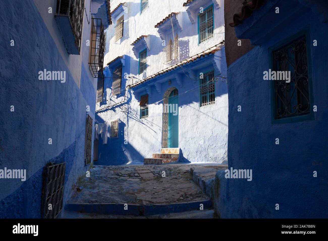 The enshadowed street and the sunlit wall of building in medina of ...