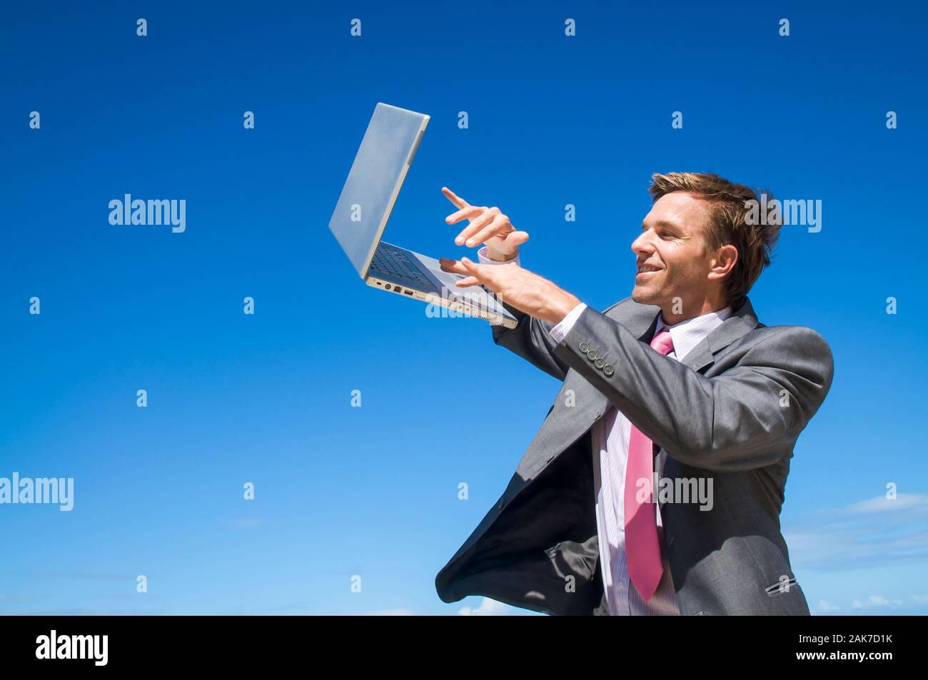 Happy businessman typing on a laptop floating in sunny blue sky Stock ...