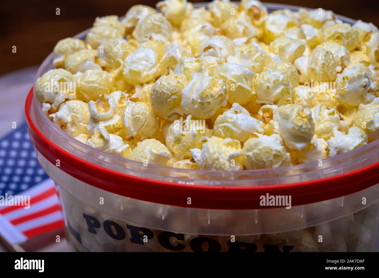 Plastic bucket with tasty sweet popcorn ready to eat and flag of USA ...