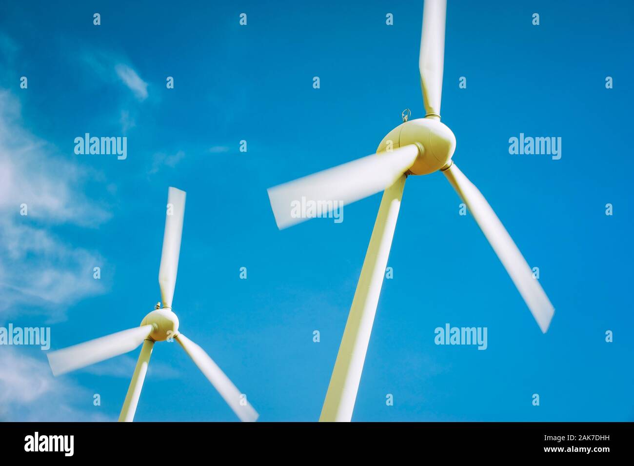 Pair of wind turbines spinning in motion blur action against bright ...