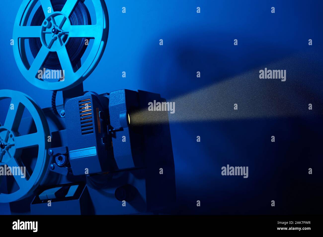 Vintage old fashioned projector in a dark room projecting a film on ...