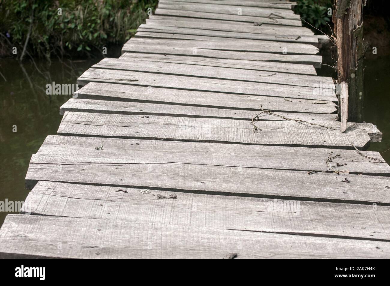 Small weathered wooden boards bridge over river waters closeup Stock ...