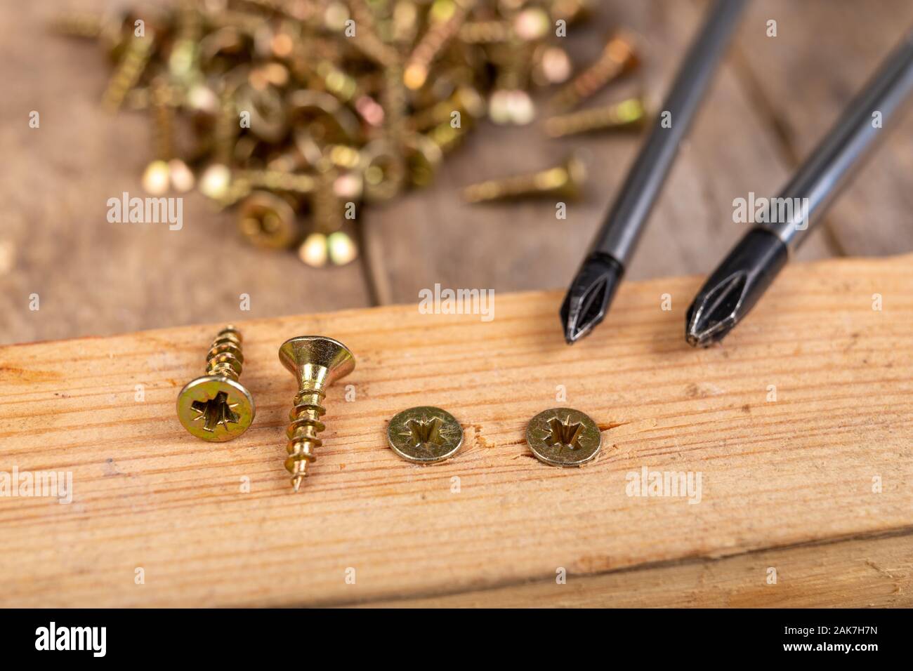 Wood screws and a screwdriver on a piece of wood. Carpentry work in a ...