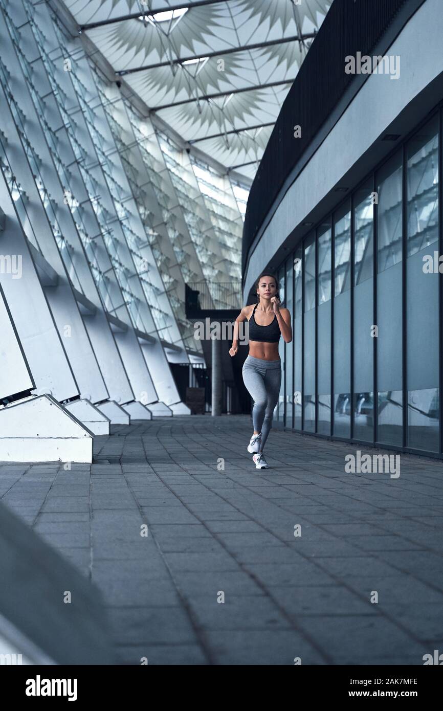 Young athletic woman running at urban city stadium with big mirror ...