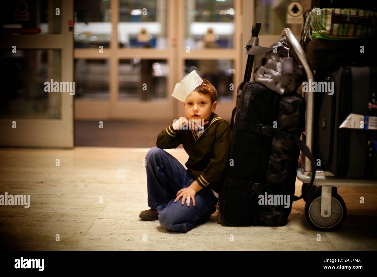 View of a boy sitting near a luggage trolley Stock Photo - Alamy