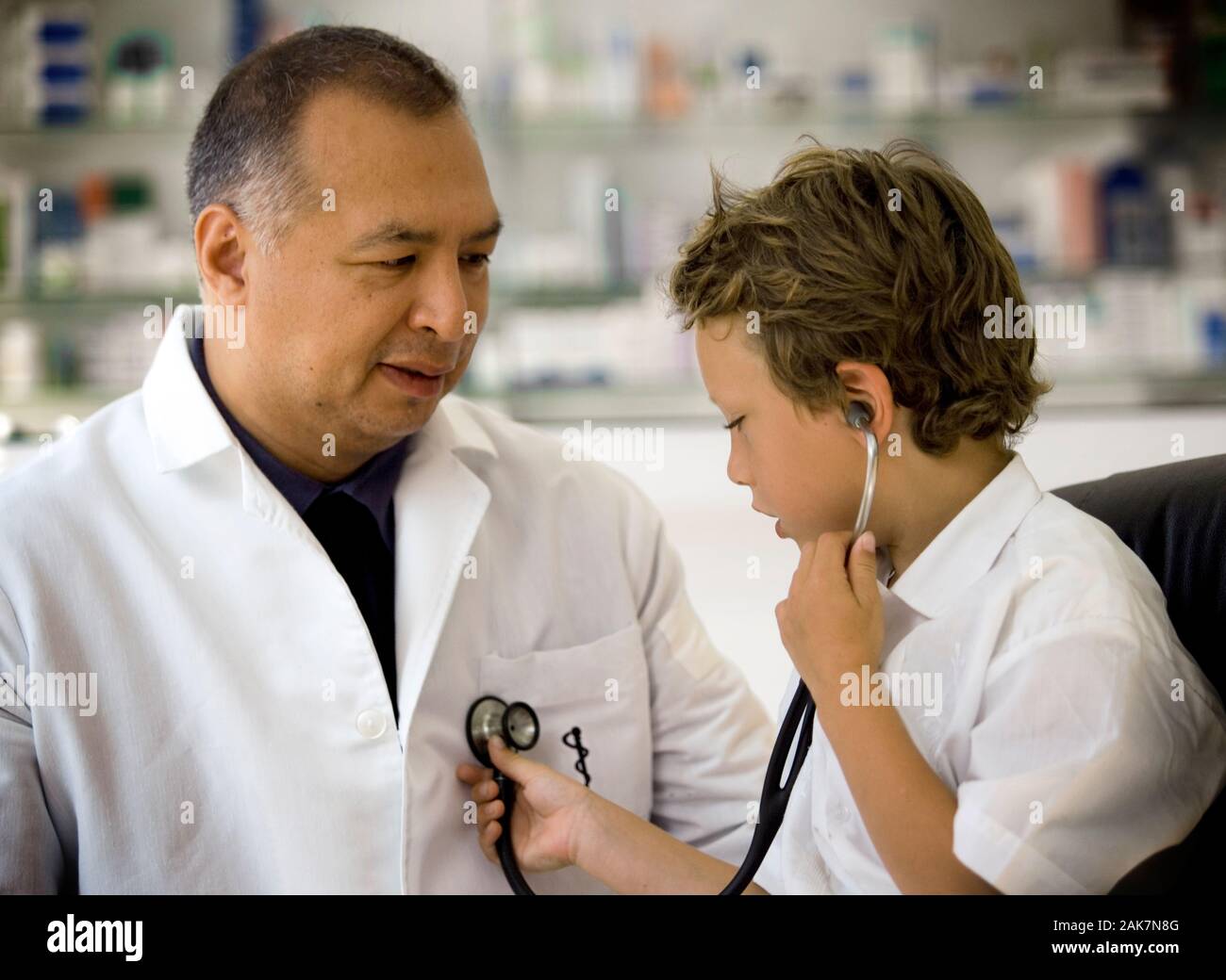 A small boy checks the heart beat of a doctor via stethoscope Stock ...