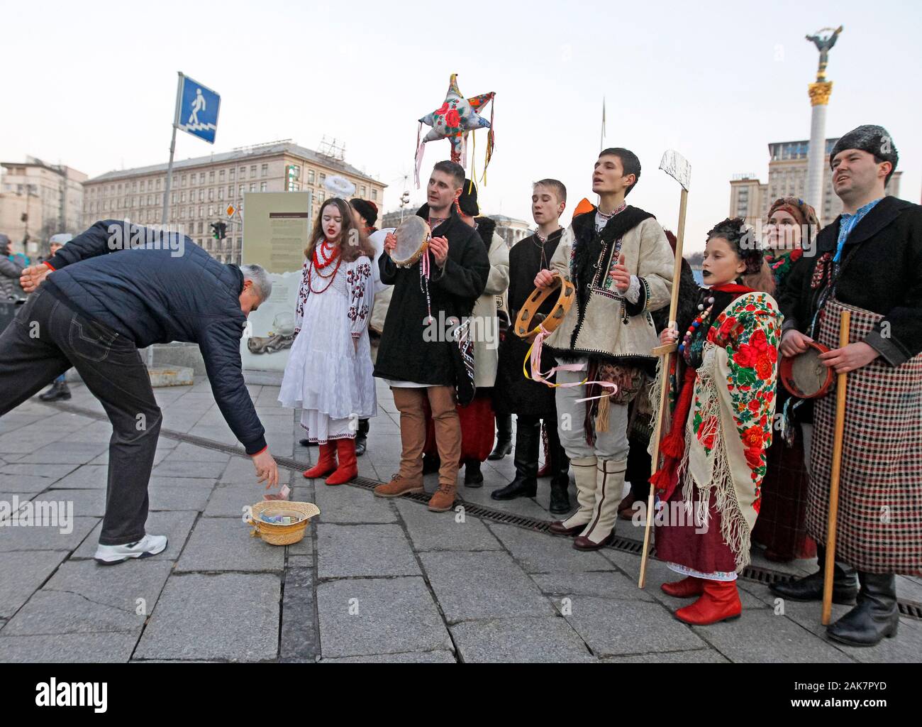 A passerby puts money in a hat, as performers wearing traditional ...