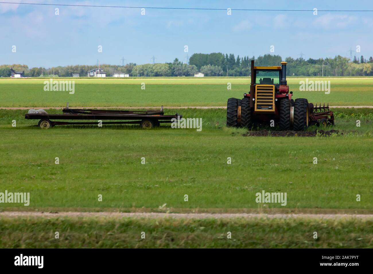 A wide angle view of a tractor and flatbed trailer parked in a green ...