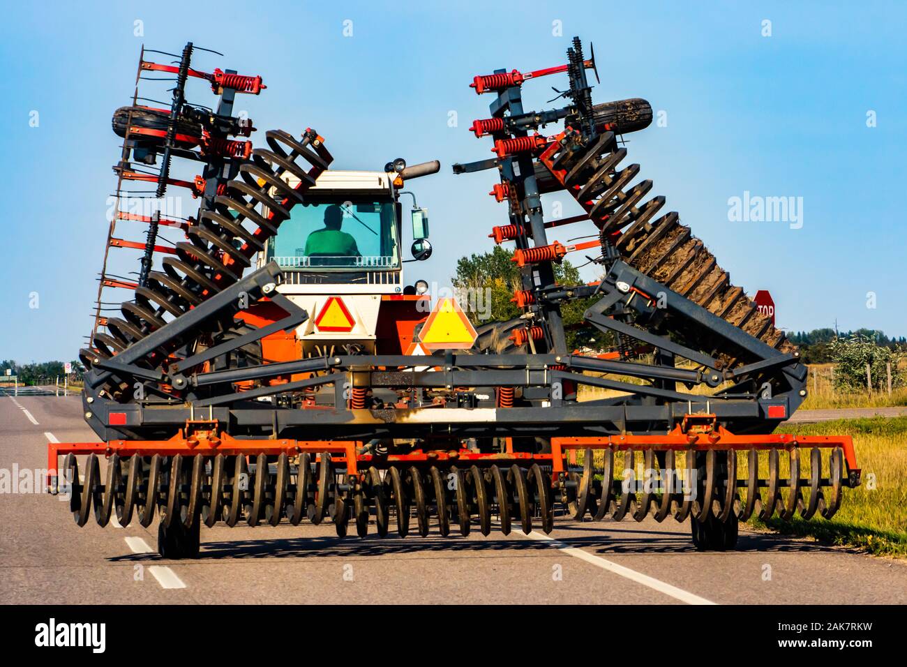 A farmer is seen driving a large industrial tractor from behind, with ...