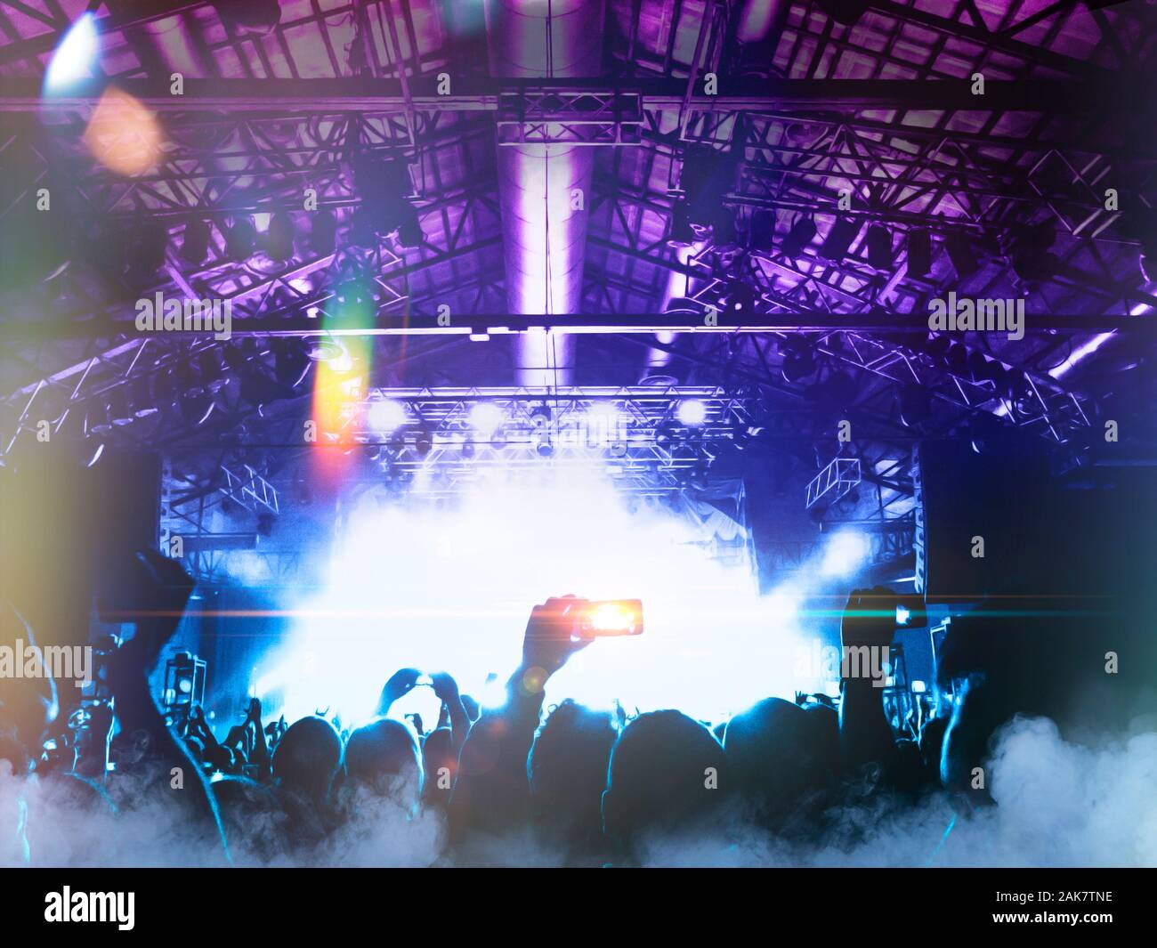 A shot taken in front of a concert stage lit in the night, people are ...