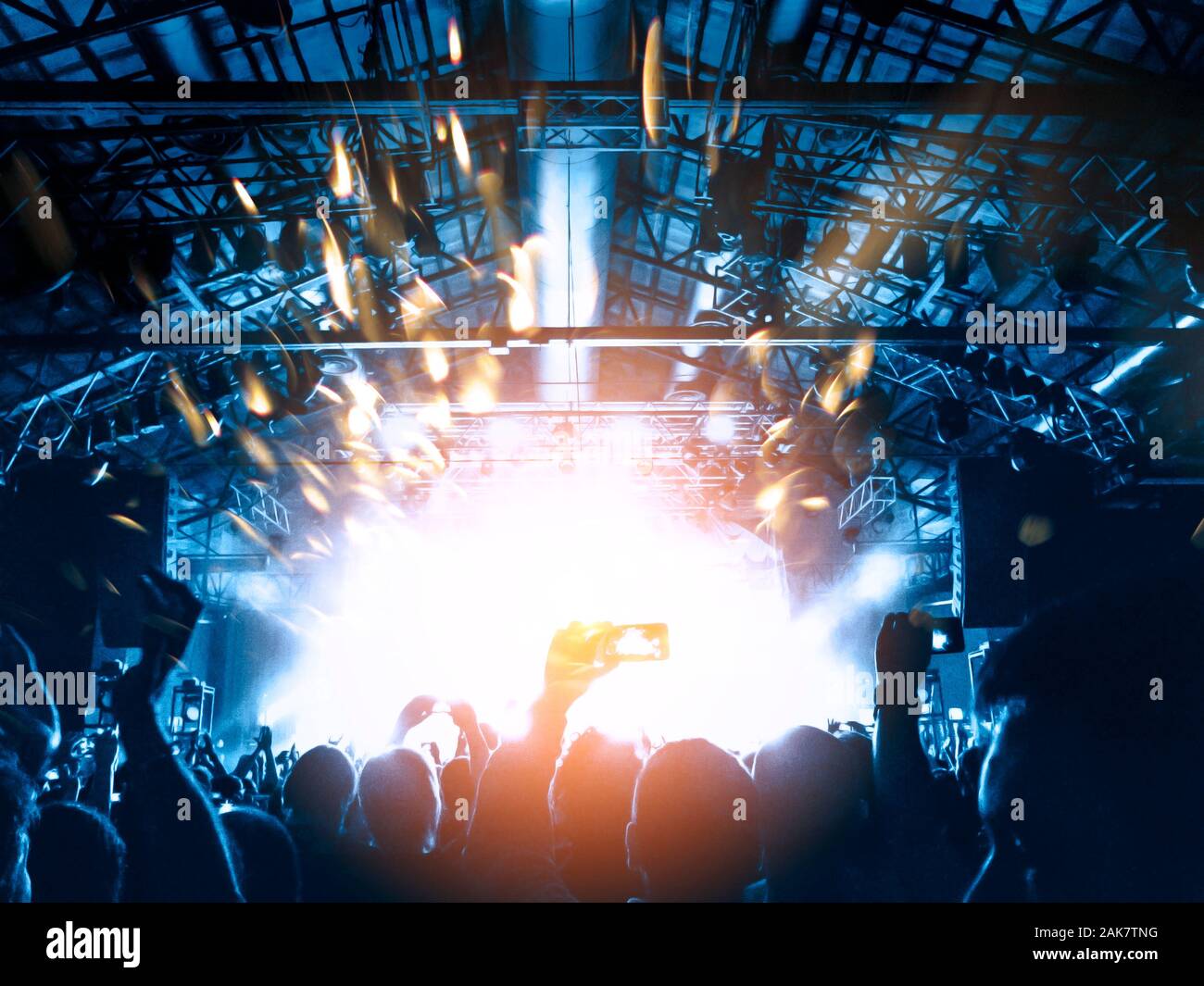 A shot taken in front of a concert stage lit in the night, people are ...