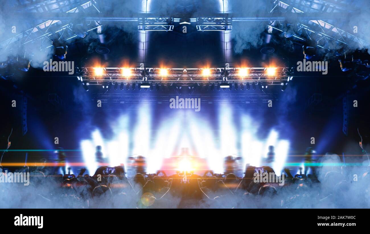 A shot taken in front of a concert stage lit in the night, people are ...